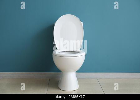 Ceramic toilet bowl near blue wall Stock Photo - Alamy