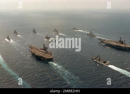 An aerial view of various ships underway in formation. They are ...