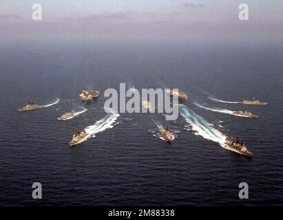 An aerial view of various ships underway in formation. They are ...