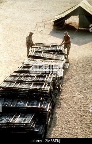 US Navy personnel stack cot frames for shipment as they dismantle their ...