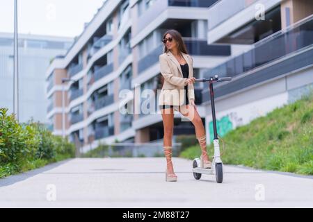 A businesswoman moving with an electric scooter around the city ...