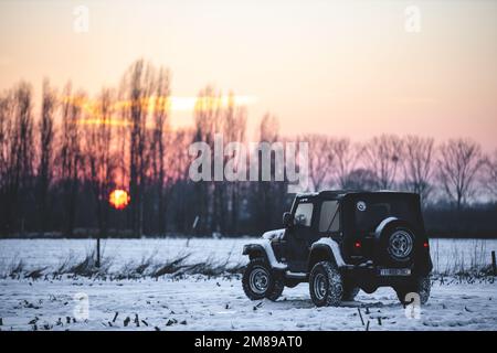 A Jeep wrangler covered in snow at sunset on a cold winter day Stock ...