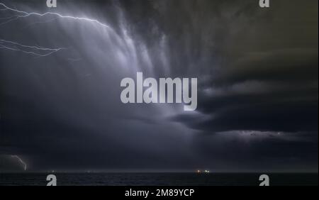 Thundercloud with lightning at night over the ocean Stock Photo - Alamy