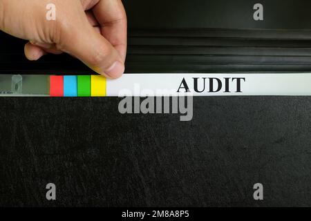 Hand picking audit report file record in black binder folder. Auditing ...