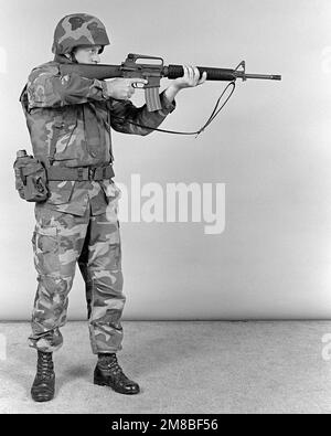 A Marine demonstrates a standing firing position with an M-9 9mm pistol ...