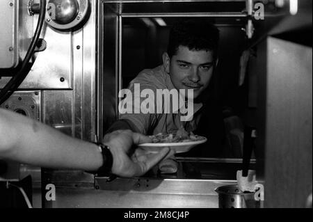 A mess management specialist works in the galley aboard the guided ...
