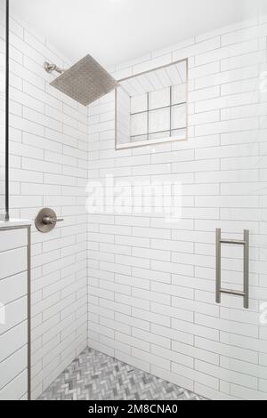 A walk-in shower with marble subway tile walls, square tiled floor, and ...