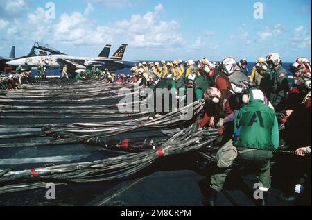 Flight deck crew members position a crash barricade aboard the aircraft ...