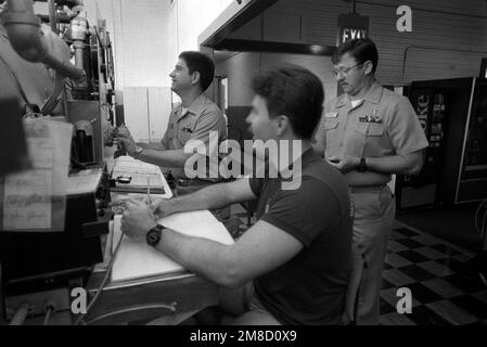 Naval personnel work at the control panel for the decompression chamber ...