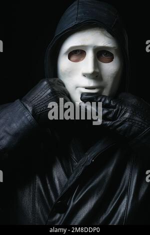 Man in terrible face mask staring at camera against dark background ...