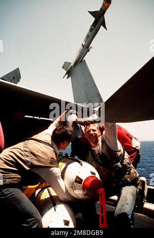 Flight deck crewmen help hoist a Mark 20 Rockeye II cluster bomb onto ...