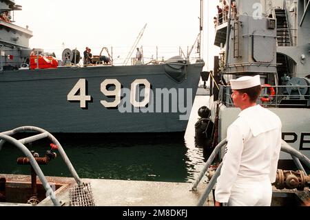 A sailor watches as the ocean minesweeper USS EXPLOIT (MSO-440) departs ...