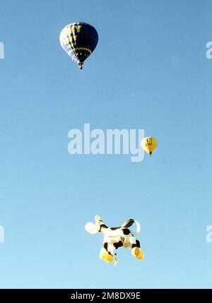 A U.S. Navy hot air balloon and dozens of other balloons float over the ...