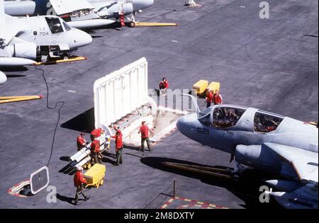 Four aviation ordnancemen work on a load of AIM-7 Sparrow III missiles ...