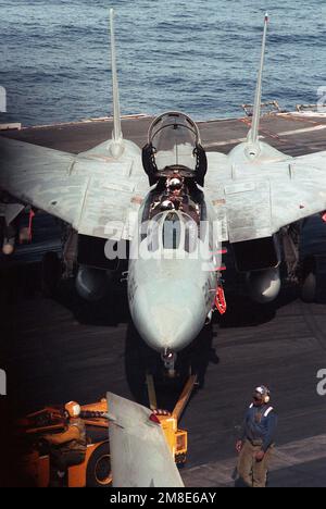 A pilot and radar intercept officer from Fighter Squadron 143 (VF-143) sit in the cockpit of ...