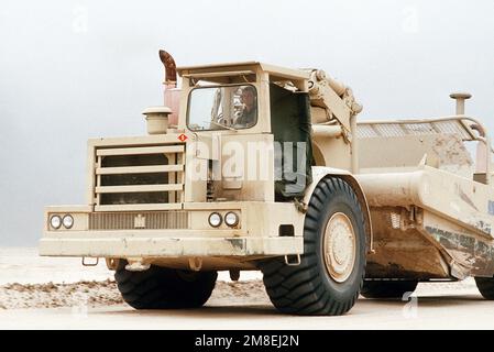A Seabee drives a motorized earthmoving scraper along a road being ...