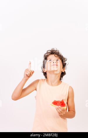 Boy eating a watermelon and pointing up, summer vacation. White ...