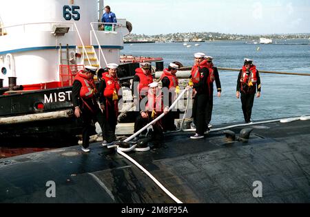 Line handlers stand by as a tug boat helps maneuver the aircraft ...