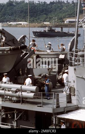 Three crewmen aboard minesweeping boat 51 (MSB-51) look toward the ...