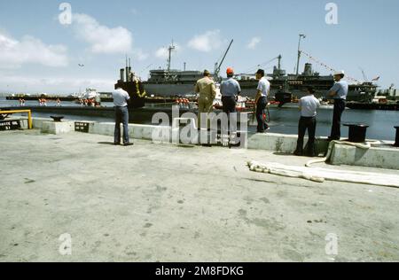 Line handlers stand by on the pier as the tank landing ship USS ...