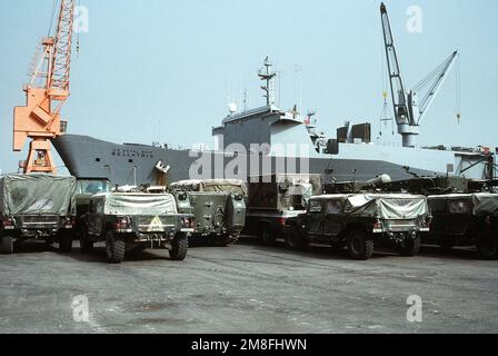 Military vehicles and equipment line a pier in preparation for ...
