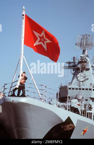 A crew member raises a flag aboard the guided missile frigate USS LEWIS ...