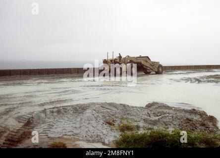 A Seabee drives a motorized earthmoving scraper along a road being ...