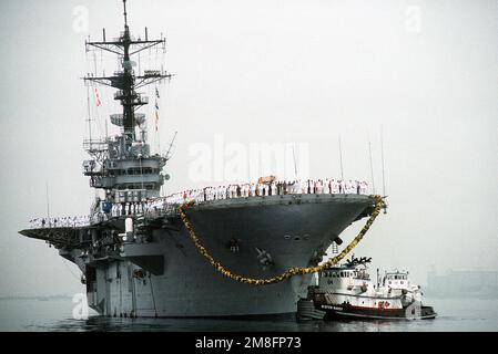 A commercial harbor tug maneuvers the amphibious transport dock USS ...