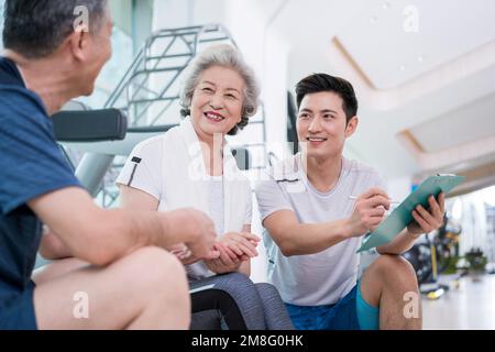 Elderly couple under the guidance of personal training in the gym for a ...