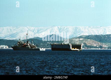 Small auxiliary floating dry dock Adept (AFDL-23) is towed by salvage ...