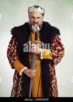 King, portrait and man with bloody sword in studio isolated on a gray ...