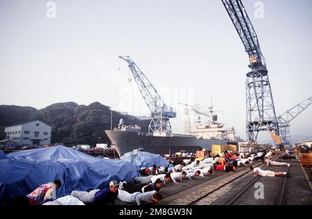 Crew members of the repair ship USS VULCAN (AR-5) stand by following ...