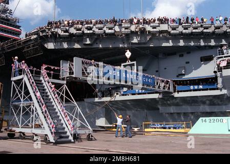 Crew members watch from the railings of the aircraft carrier USS ...