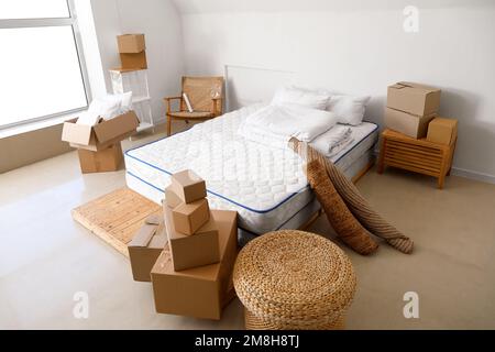Cardboard boxes with rolled carpets and bed in room on moving day Stock ...