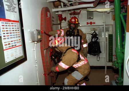 Crewmen, wearing oxygen breathing apparatus, prepare for a fire ...