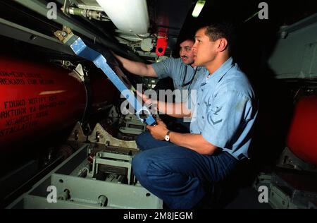 Torpedoman Third Class (TM3) Kurt Lopez attaches an "A" cable to an ...