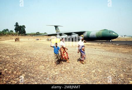 Rwandan refugees walk near an Air Mobility Command C-141 Starlifter ...