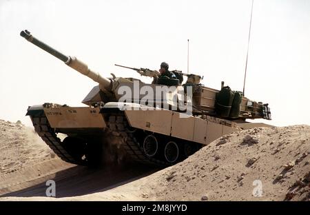 An M1A1 Abrams tank breaches a berm in the desert during maneuvers ...