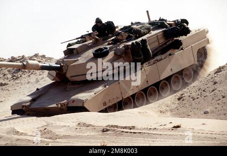An M1A1 Abrams tank breaches a berm in the desert during maneuvers ...