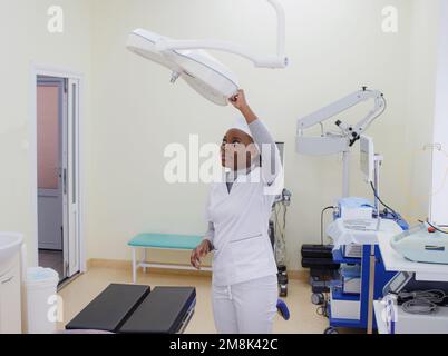 African-American girl doctor adjusts the lighting lamp in the surgery ...