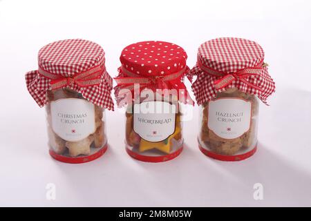 A closeup of jars filled with Christmas biscuits covered with a red ...