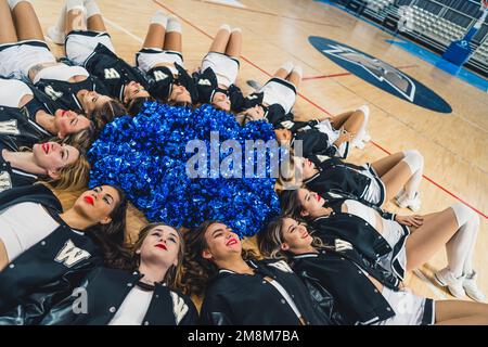A group of cheerleaders lying on the floor forming a circle with their ...