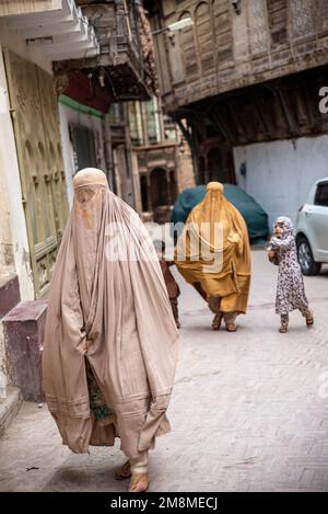 Women in burqa and children on a narrow street in Peshawar Old Town ...