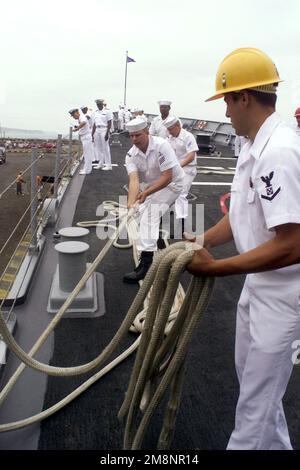 US Navy Line handlers use teamwork to heave the shot line from the ...