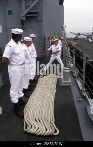 US Navy Line handlers use teamwork to heave the shot line from the ...