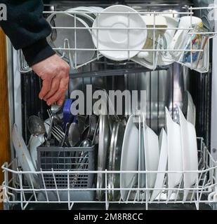 Woman load dirty dishes into open dishware, Modern kitchen appliance ...