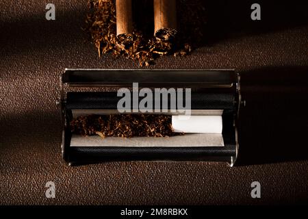 Rolling machine, cigarillos, scattered tobacco on background, cigarette ...