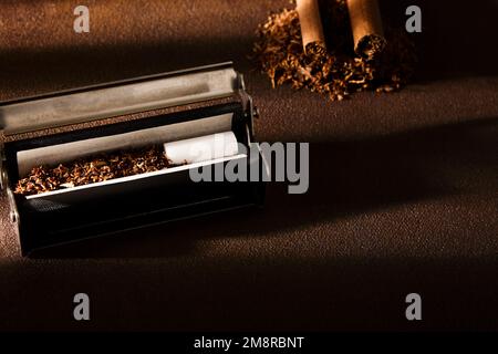 Rolling machine, cigarillos, scattered tobacco on background, cigarette ...