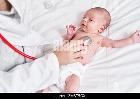 A children doctor with stethoscope auscultating the chest of a smiling ...