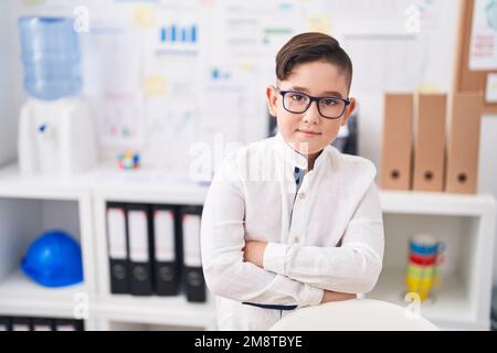 Adorable hispanic boy business worker standing with serious expression ...